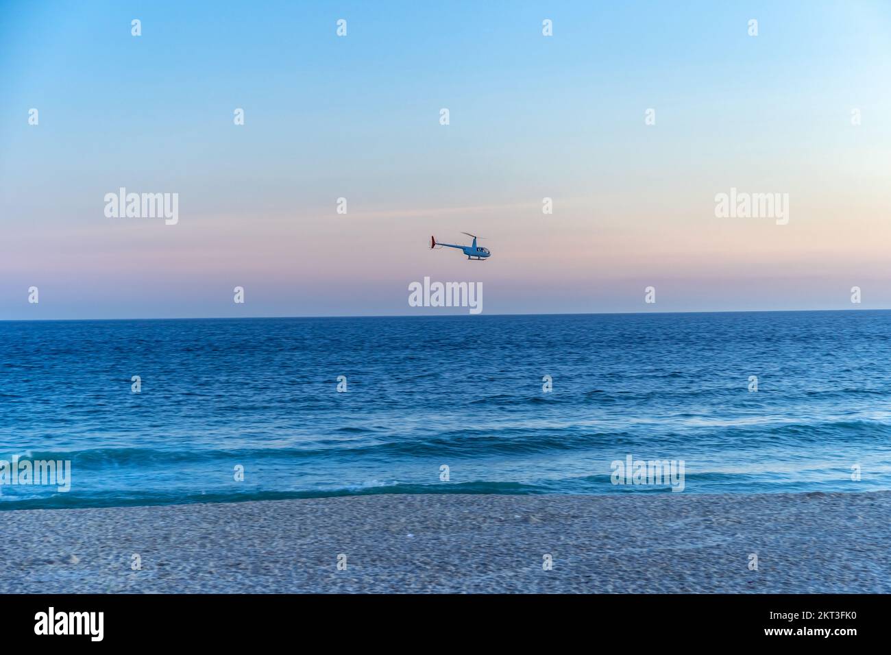 a helicopter flies over the ocean near a sandy beach Stock Photo - Alamy
