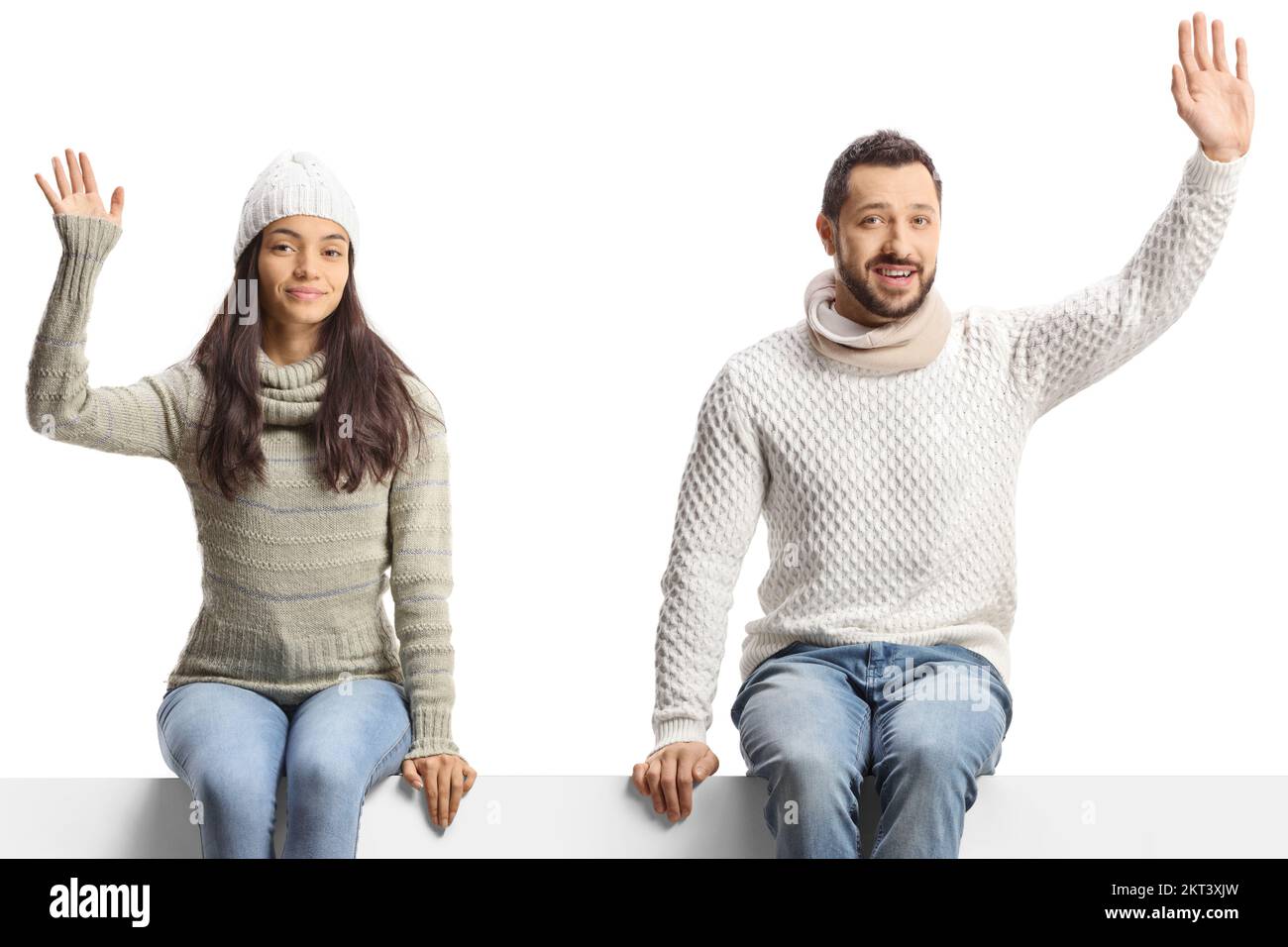 Young man and woman with winter jumpers sitting on a blank panel and ...