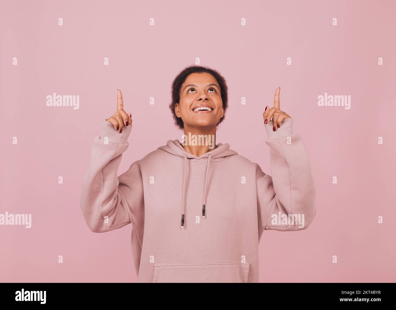 Young black excited woman pointing upwards. Studio portrait of smiling ...
