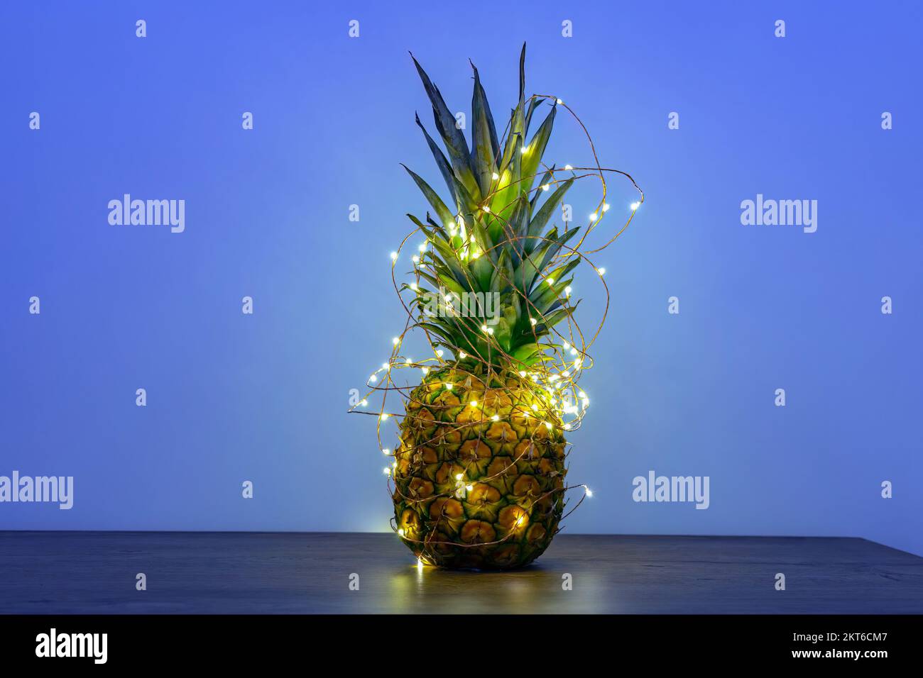 Pineapple with Christmas led-light garland on table, copy space Stock ...