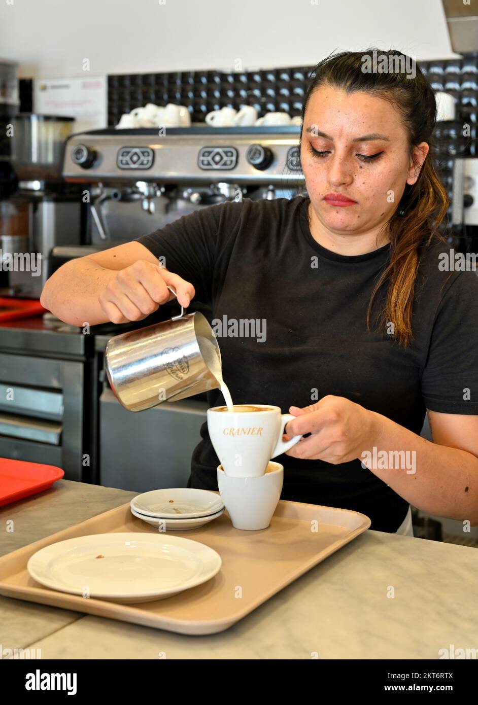Woman pouring jug of hot milk into coffee in small bakery coffee shop Stock Photo - Alamy