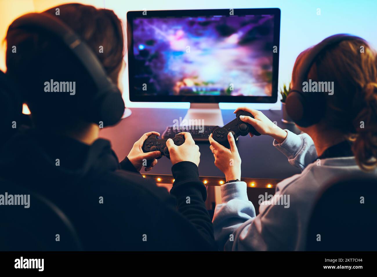 Friends playing video game at home. Gamers holding gamepads sitting at ...