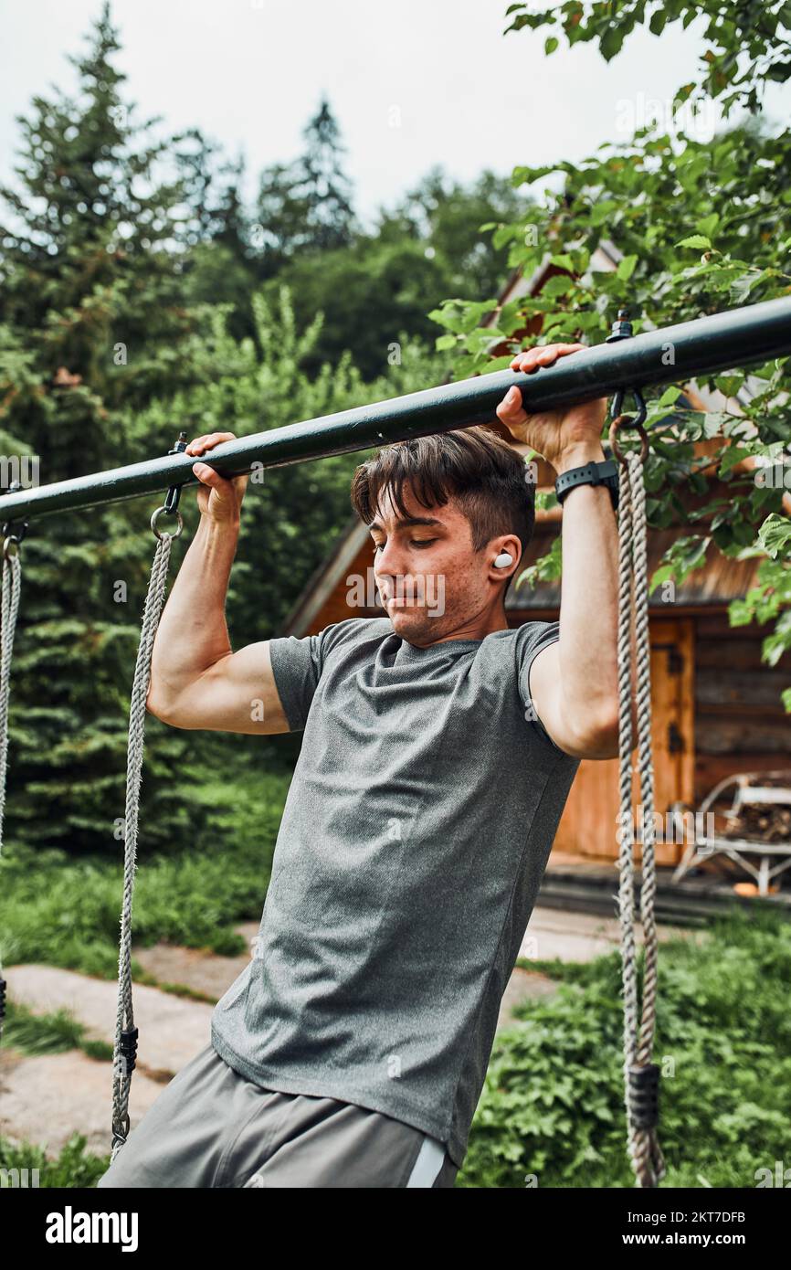 Young man doing pull-ups on pull-up horizontal bar during his ...