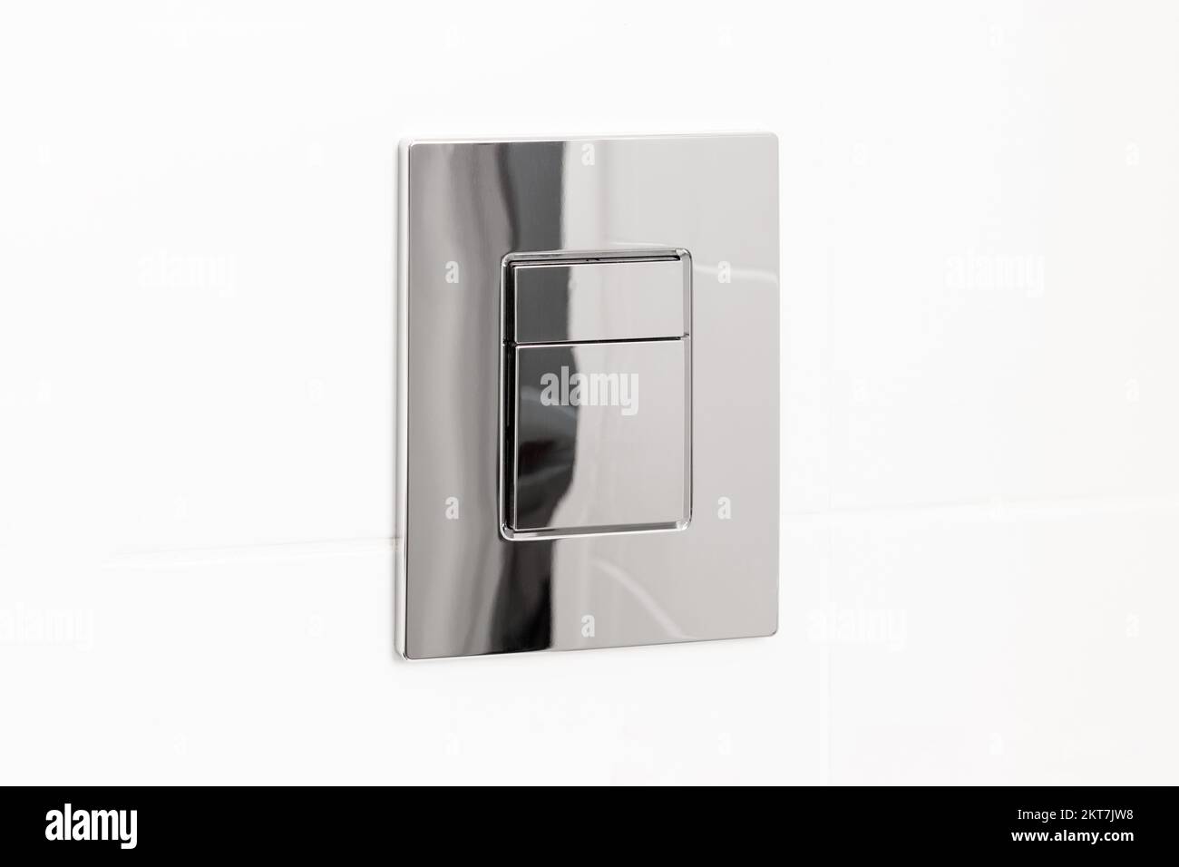Metal chromed toilet flush button on white tile wall. Details in a ...