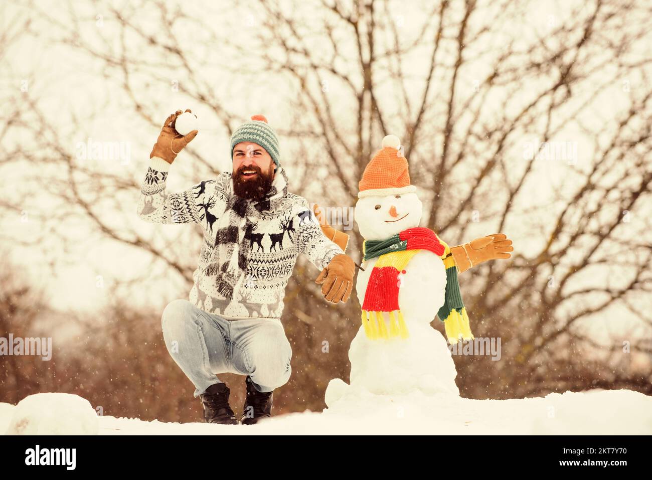 Snowman concept. Man bearded hipster cute knitted hat play with snow ...