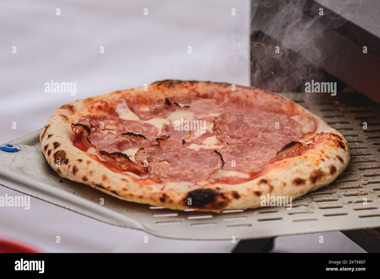 Cooking or baking hot pizza with tomato sauce, mozzarella and salami ...