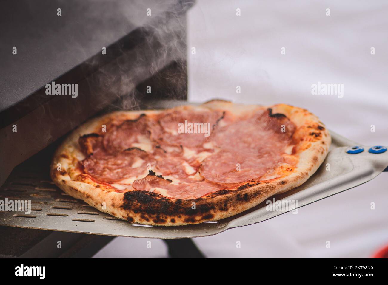 Cooking or baking hot pizza with tomato sauce, mozzarella and salami ...