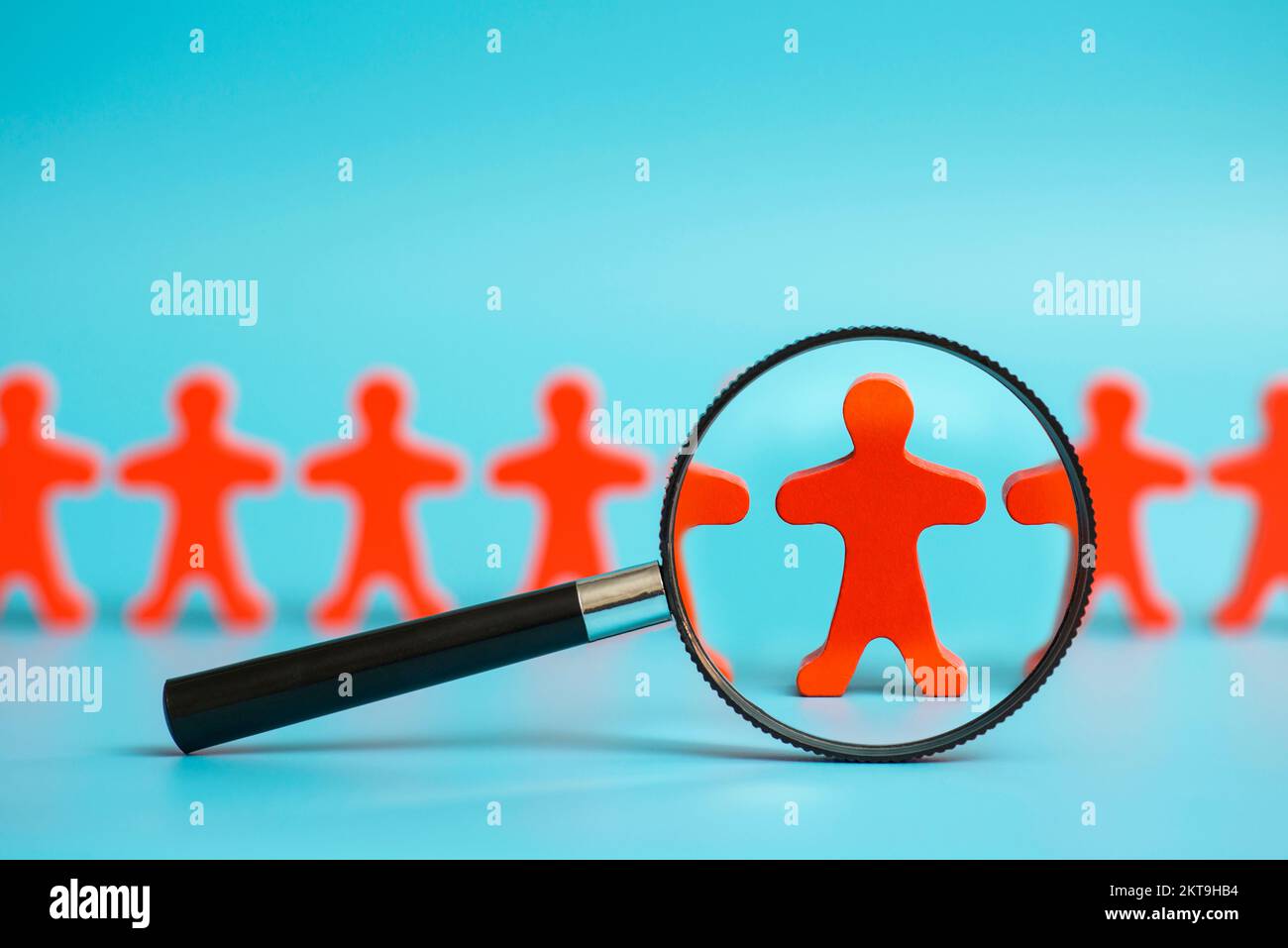 View through magnifier on the one wooden red person between other ...