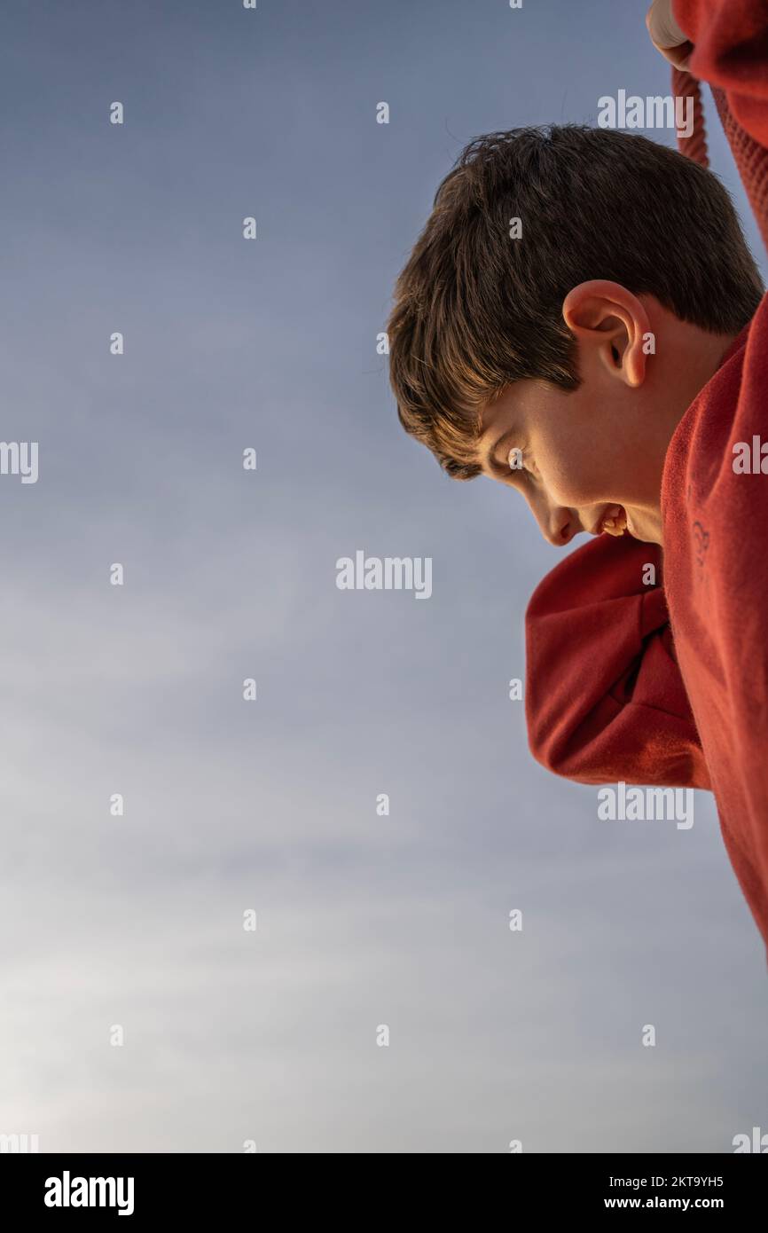 Side view portrait of a happy kid smiling looking down isolated in blue ...