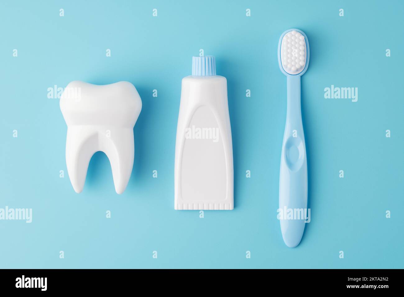 Toy tooth, toothbrush with tube of toothpaste on blue background, flat ...