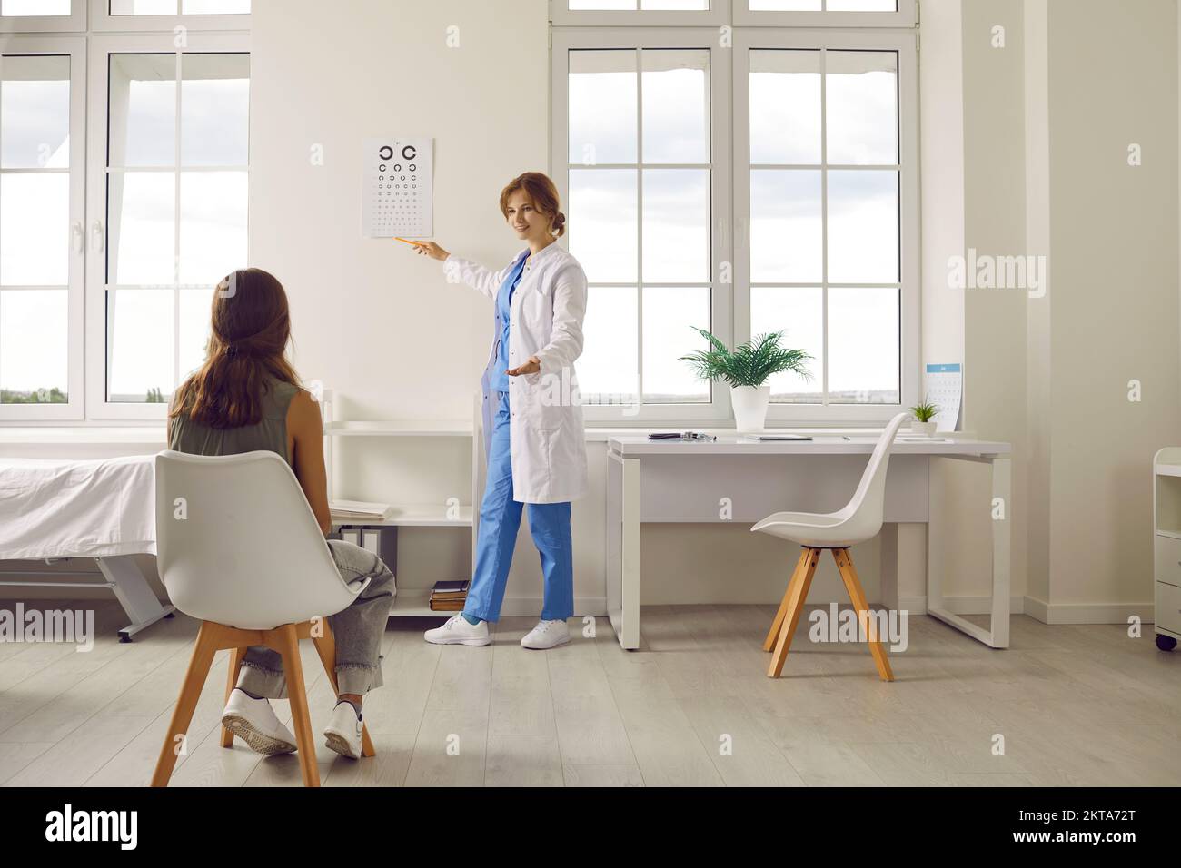 Oculist or ophthalmologist pointing at eye chart while checking child's ...