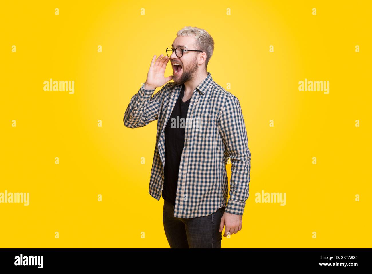 Image of caucasian young man calling for someone, looking left, making ...