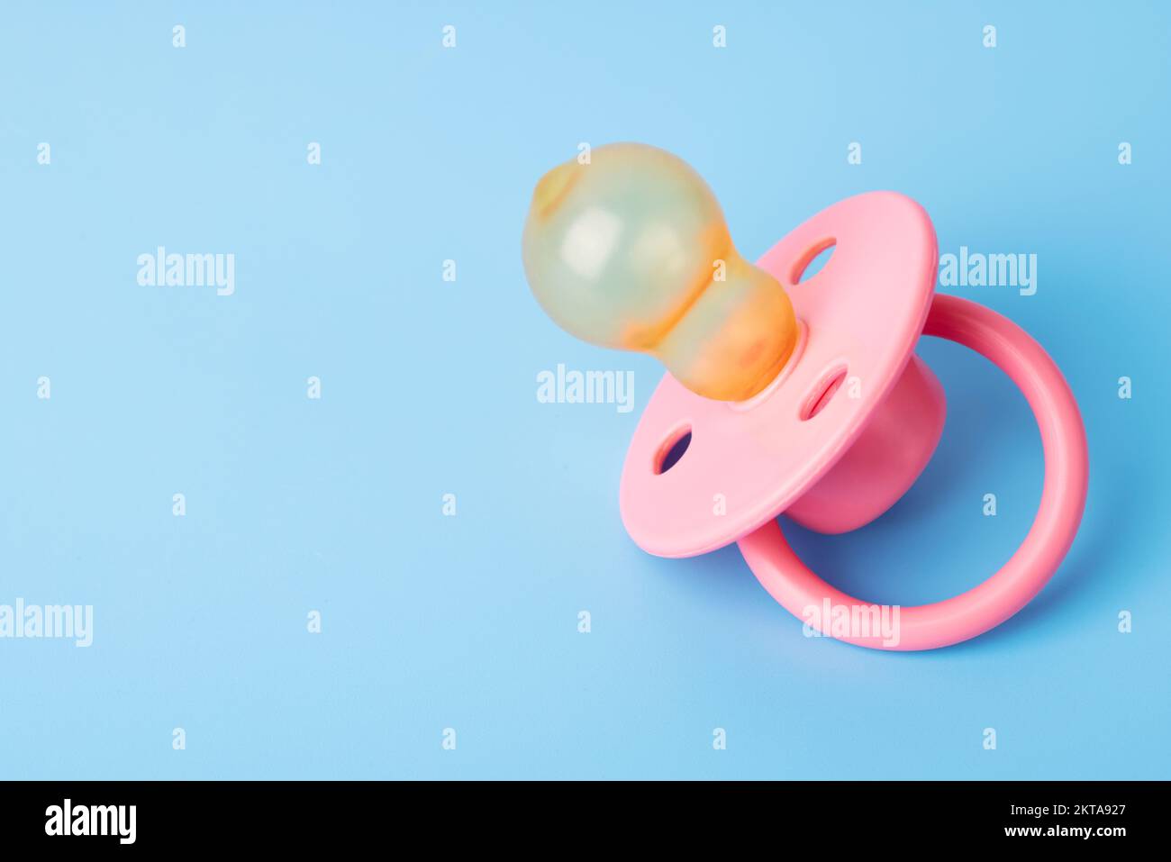 Pink baby pacifier on a blue background, space for text Stock Photo - Alamy