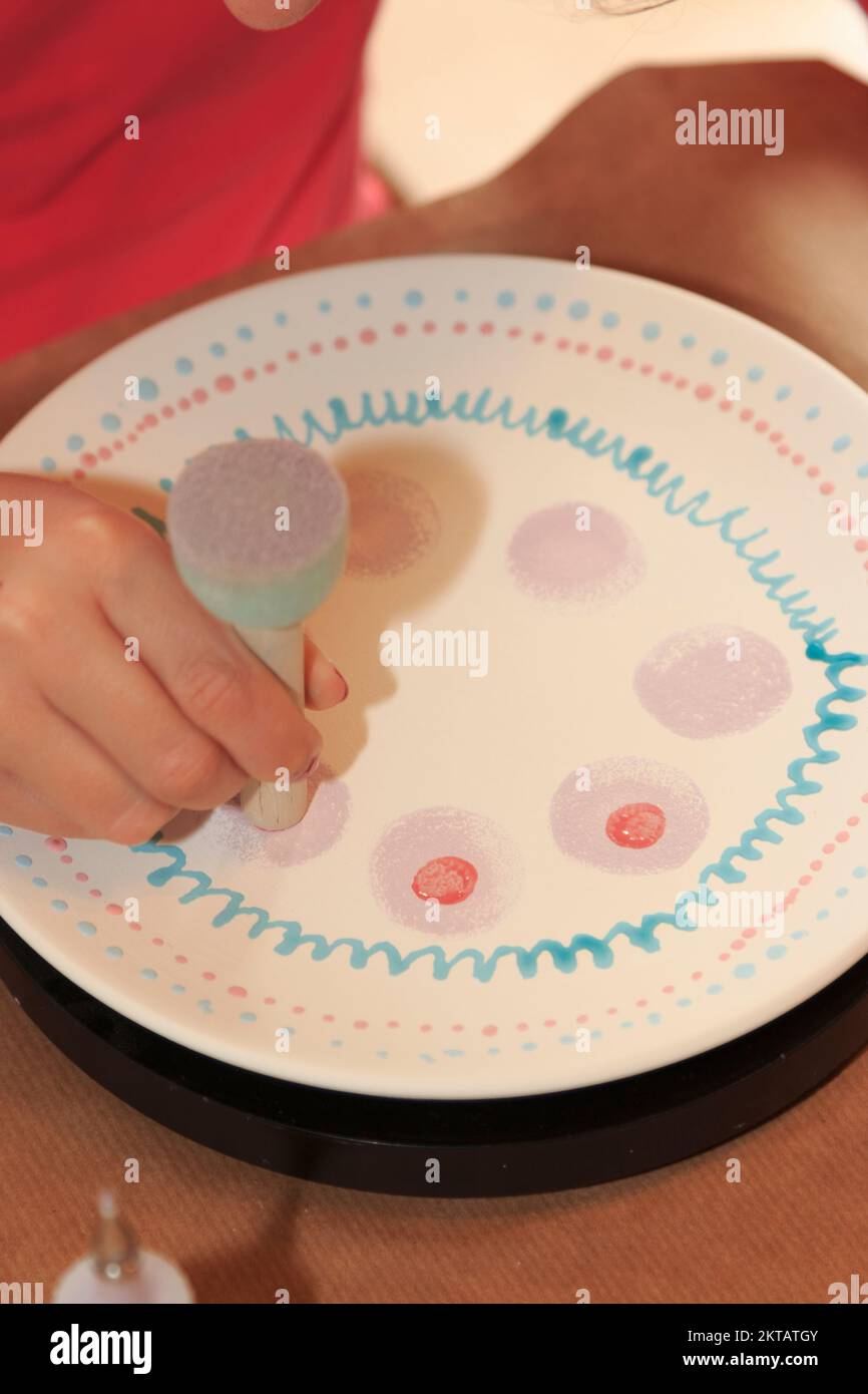 A child paints and decorates a plate with a swab Stock Photo - Alamy