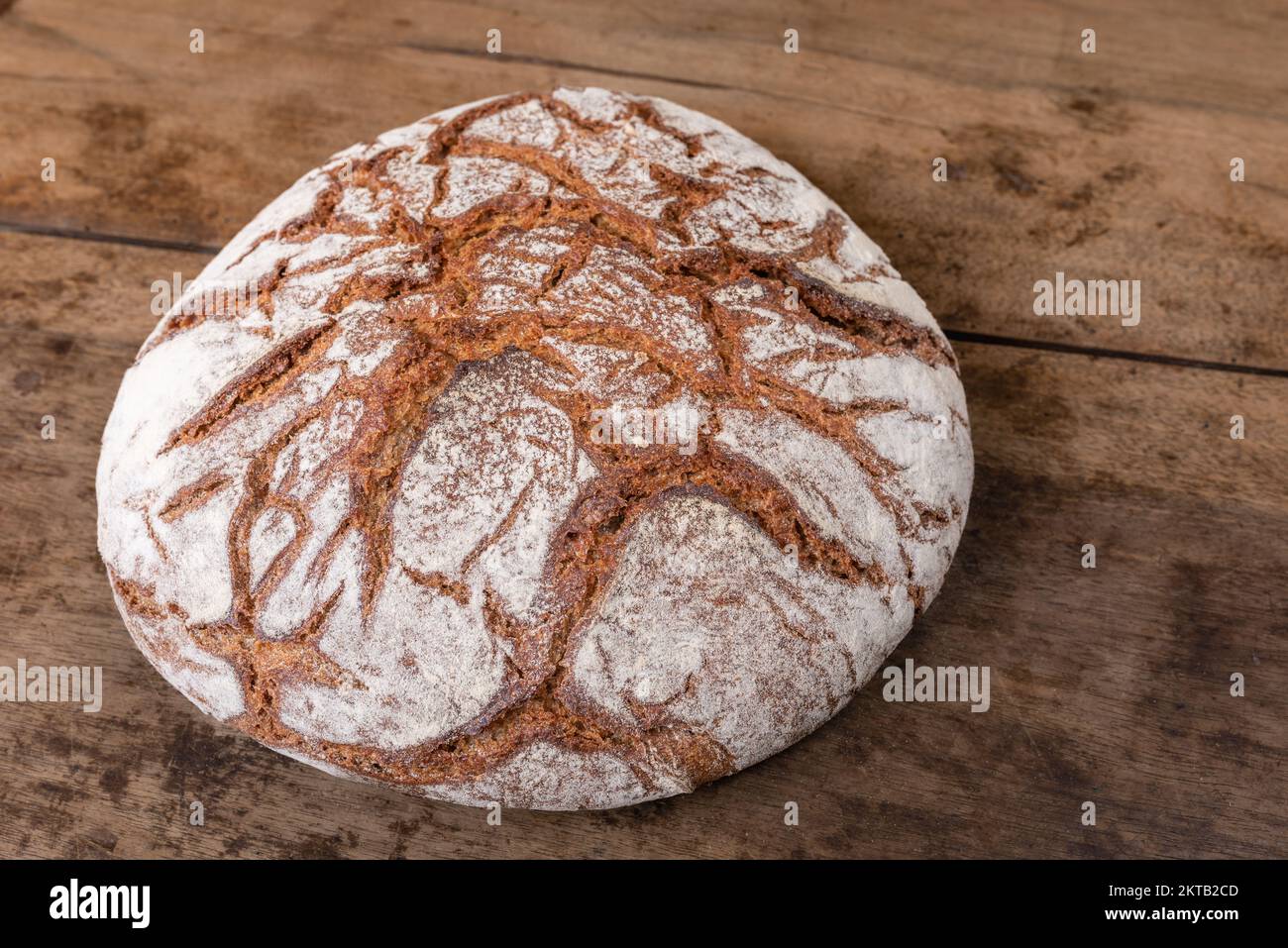 Round rye bread with a crispy crust and flour on a old table. Alsace ...