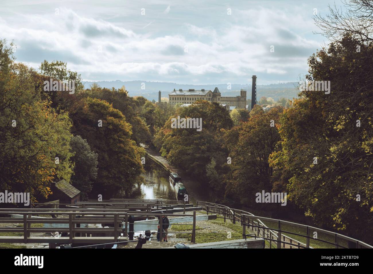 2 people by lock gates, boats moored, sunlit Damart mill, autumn colour ...