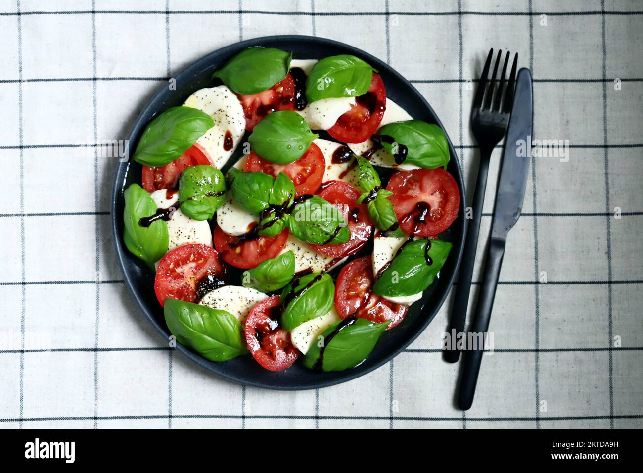 Italian signature caprese salad on a black plate Stock Photo - Alamy