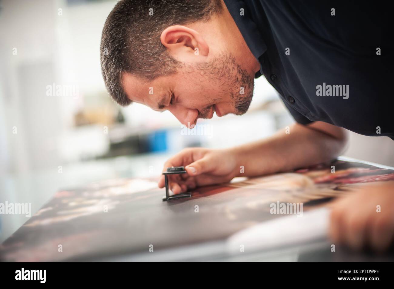 Young man in the process of printing used color scales and loupe and ...