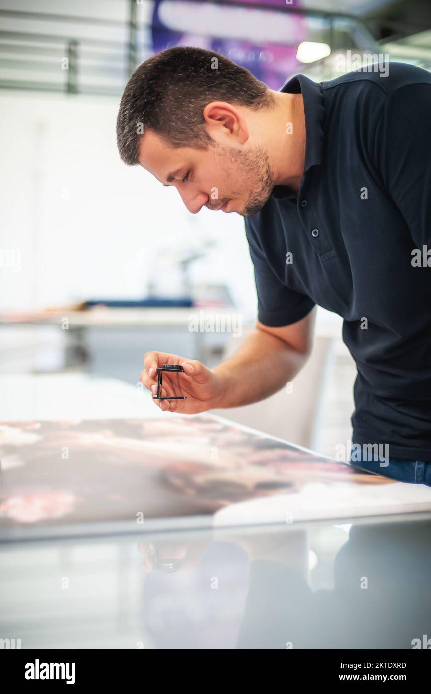 Young man in the process of printing used color scales and loupe and ...