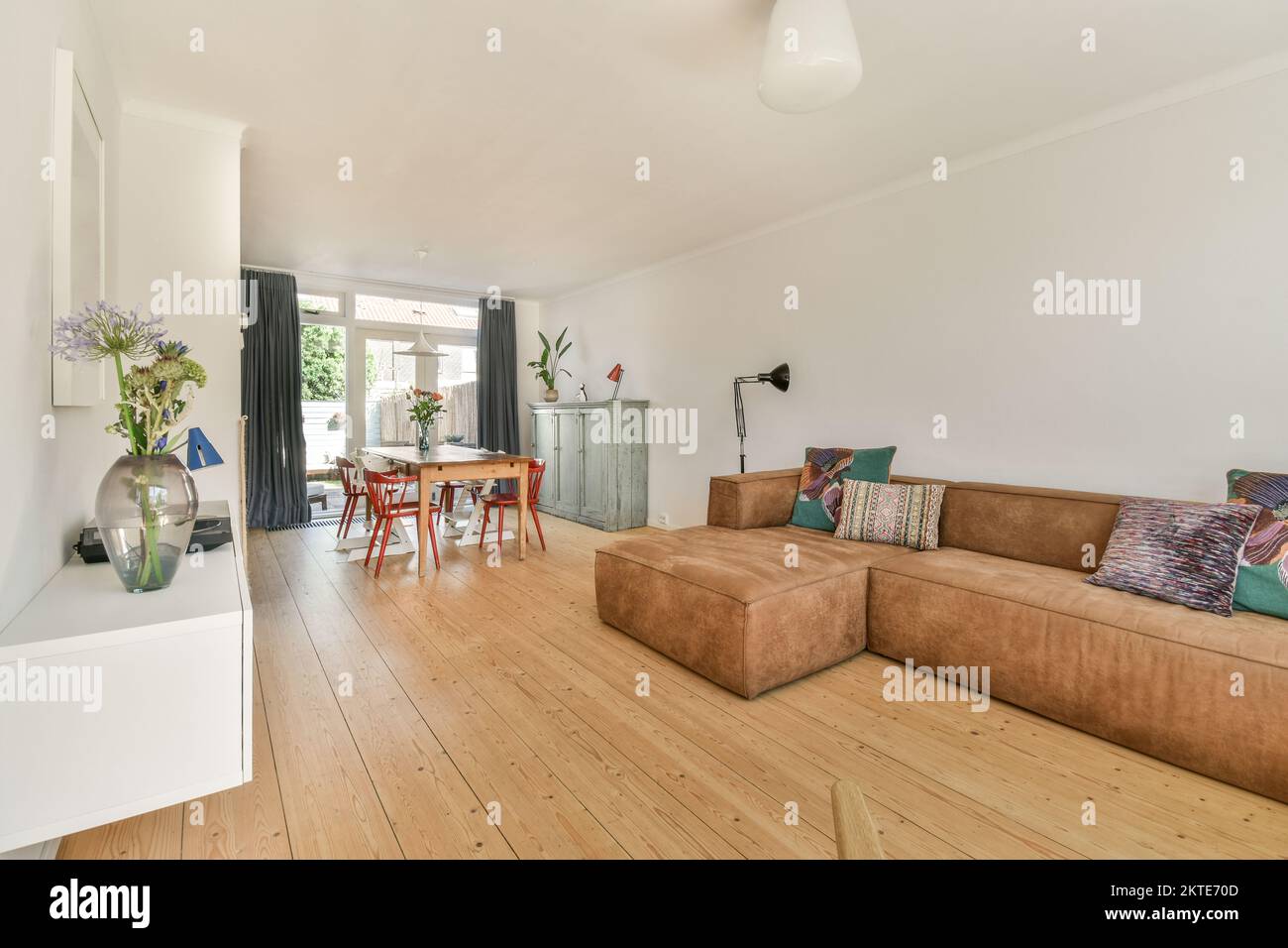 Table with chairs and flowers located near lounge area and kitchen in ...