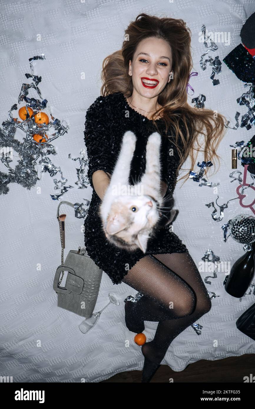 Confetti fun. Happy party woman and cute cat playing with disco ball ...