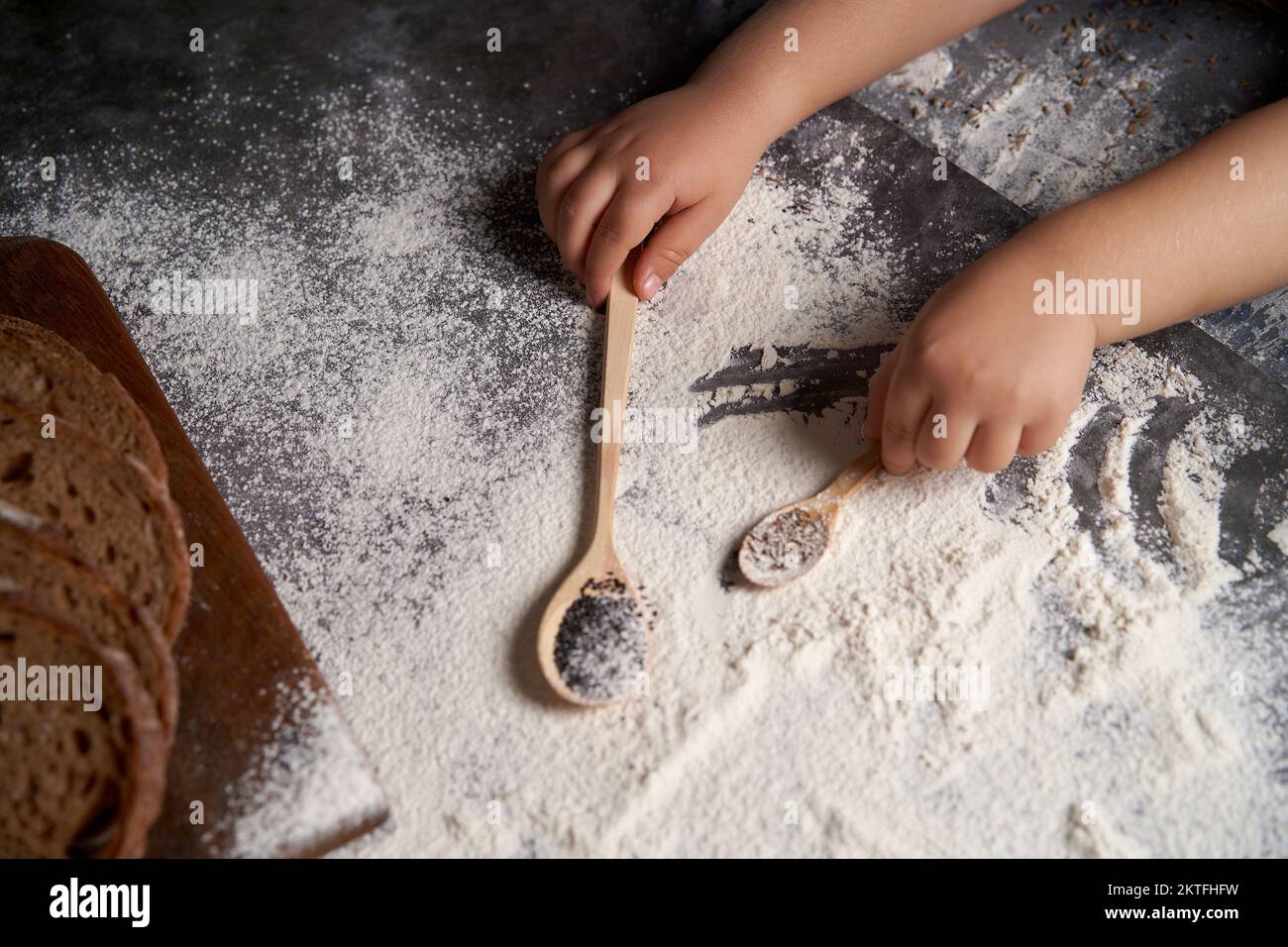 A small child helps to bake.Children's hands hold wooden spoons with ...