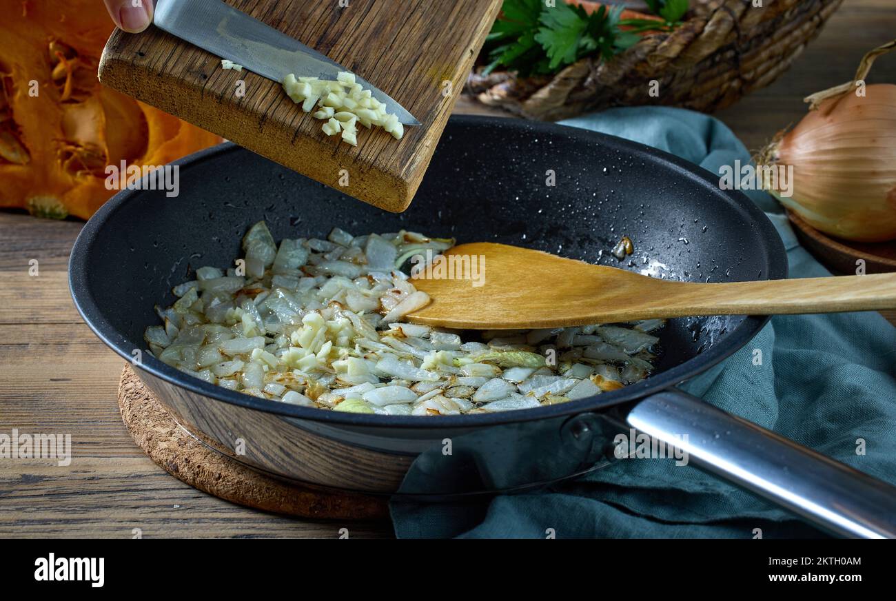 fresh chopped garlic is added to fried onions on a pan Stock Photo - Alamy