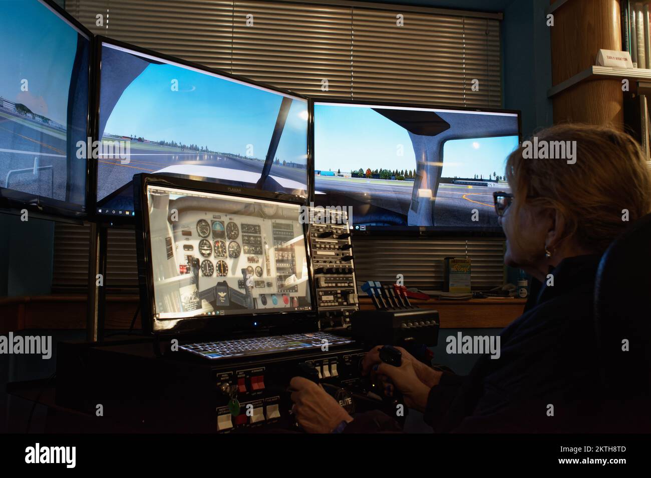 A visitor pilots a flight simulator with the assistance of a museum ...