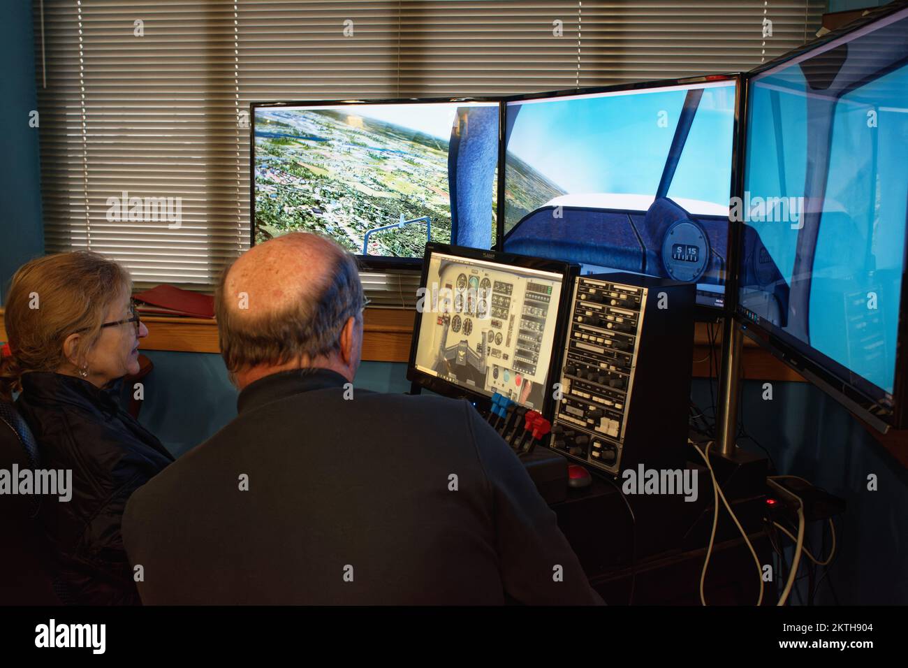 A visitor pilots a flight simulator with the assistance of a museum ...