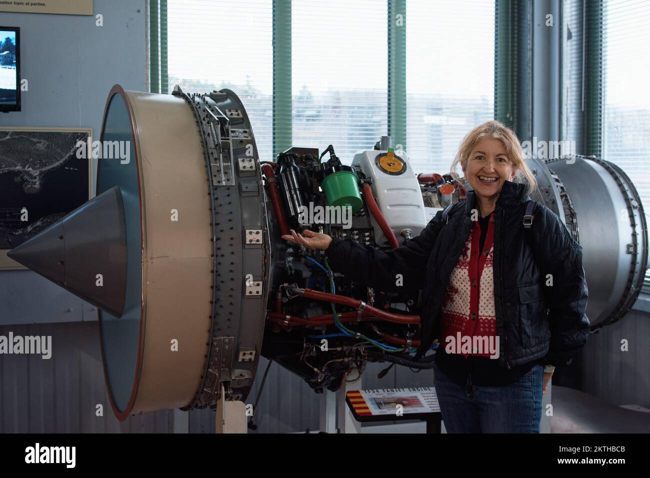 A visitor stands in front of a General Electric TF38 Jet engine at the ...