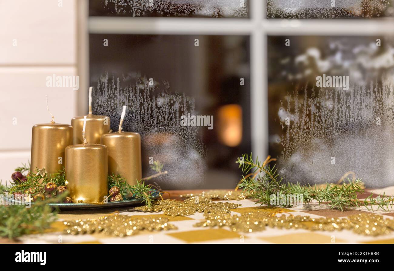 Golden Advent candles on a table in front of a window in winter weather ...