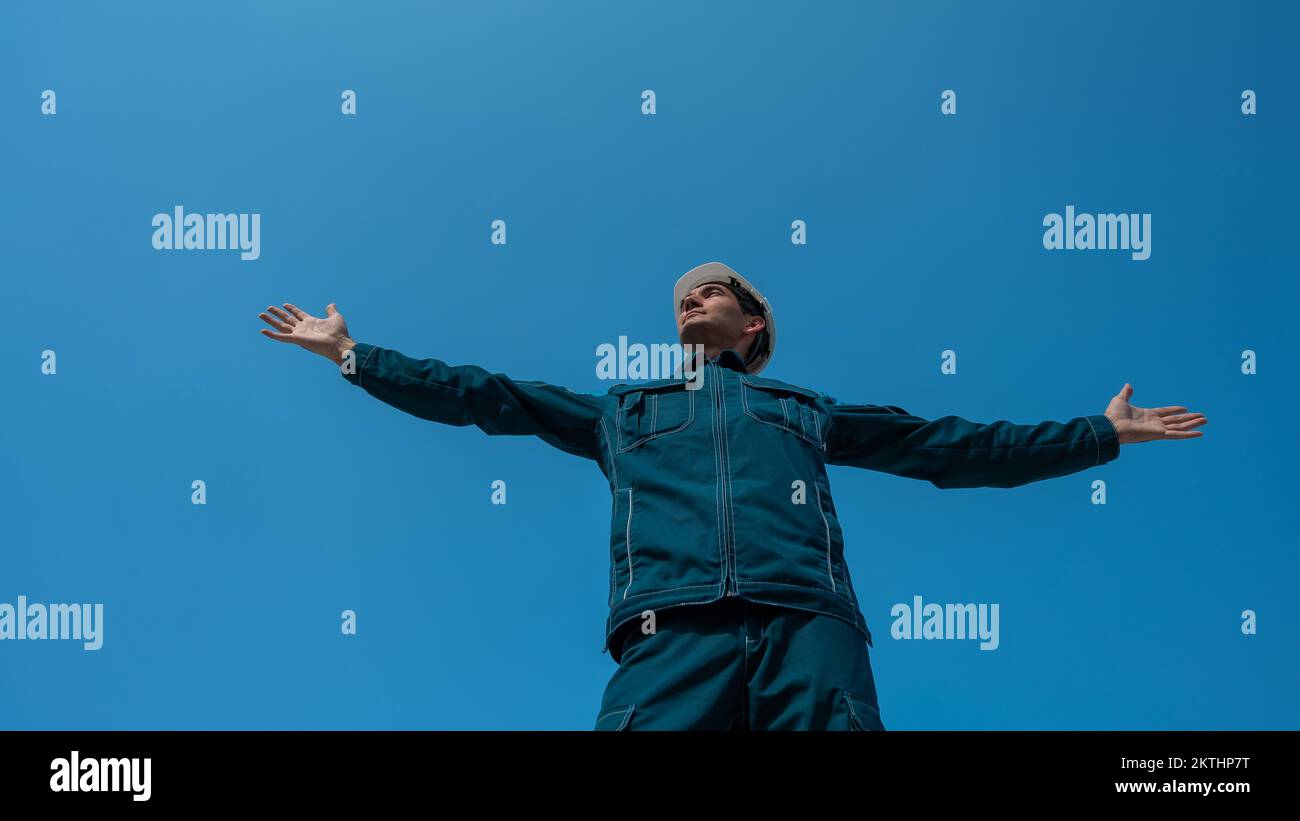 A caucasian man in work clothes and a construction helmet stands ...