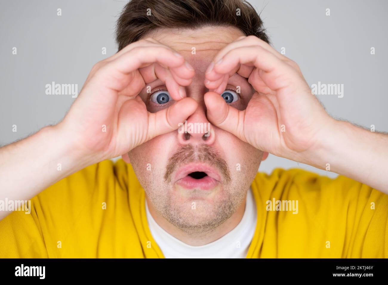 Caucasiann man making binoculars shape with his hands and looking ...