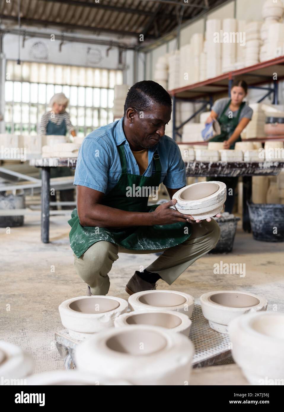 Pleased african american worker demonstrates half of plaster mold for ...