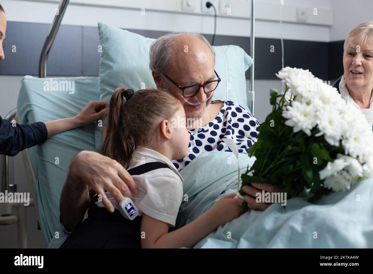 Grandfather hugging young granddaughter in hospital room. Sick old man ...