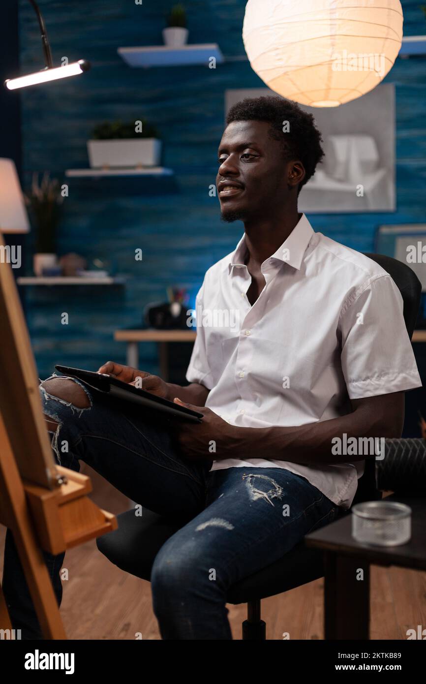 Portrait of drawing student reviewing artistic notes on tablet for ...