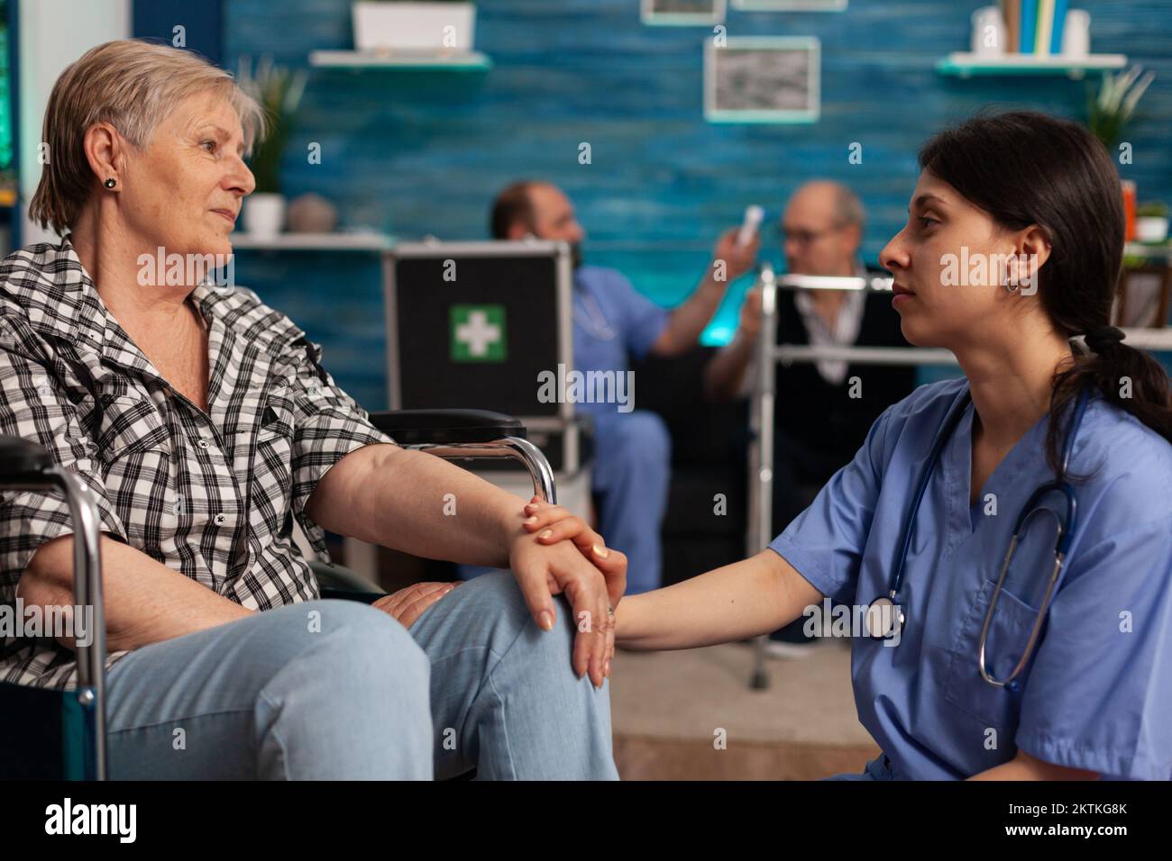 Female nurse supporting elderly woman with disability in nursing home ...
