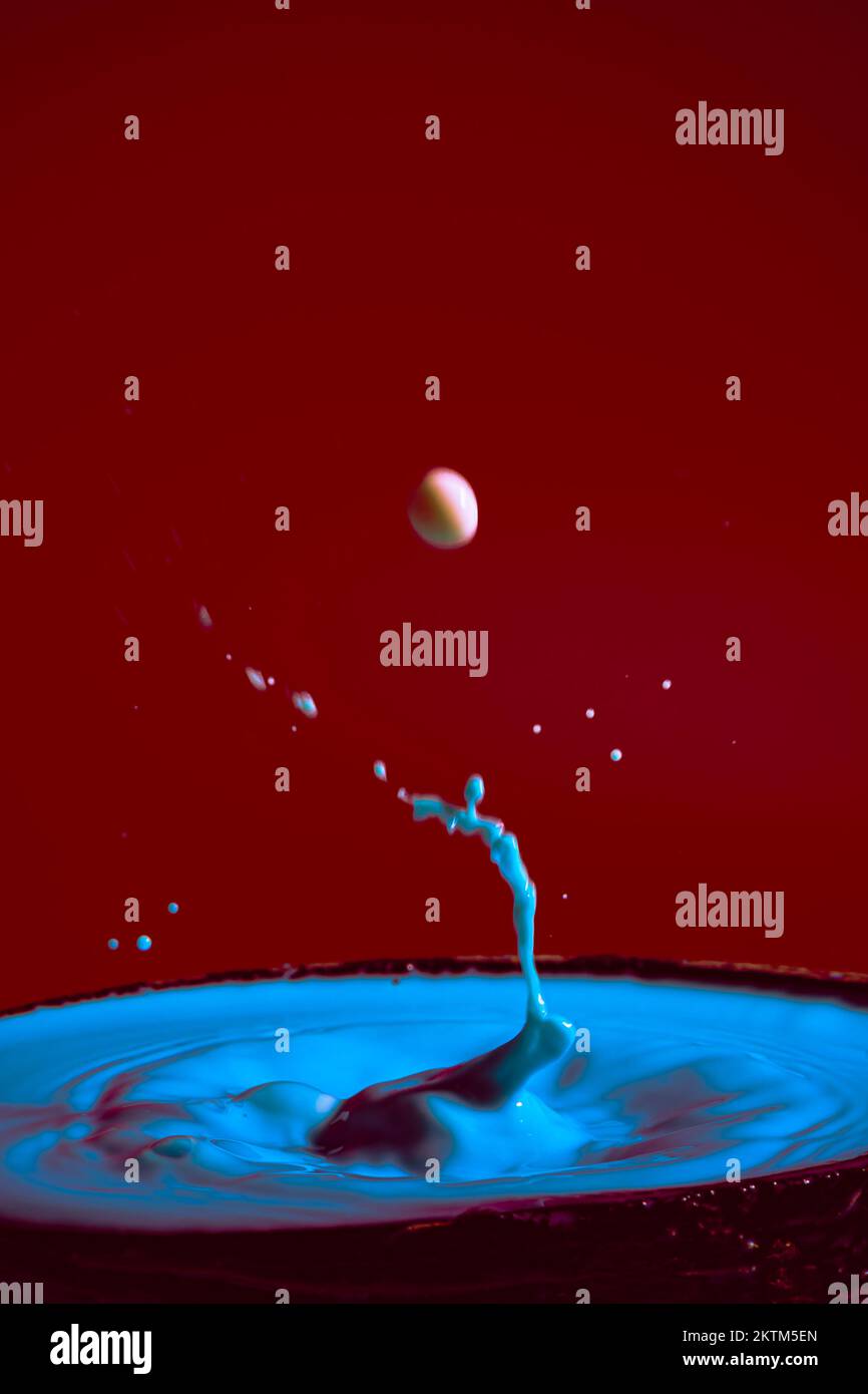 collision of moving water drops of blue color on a purple red ...
