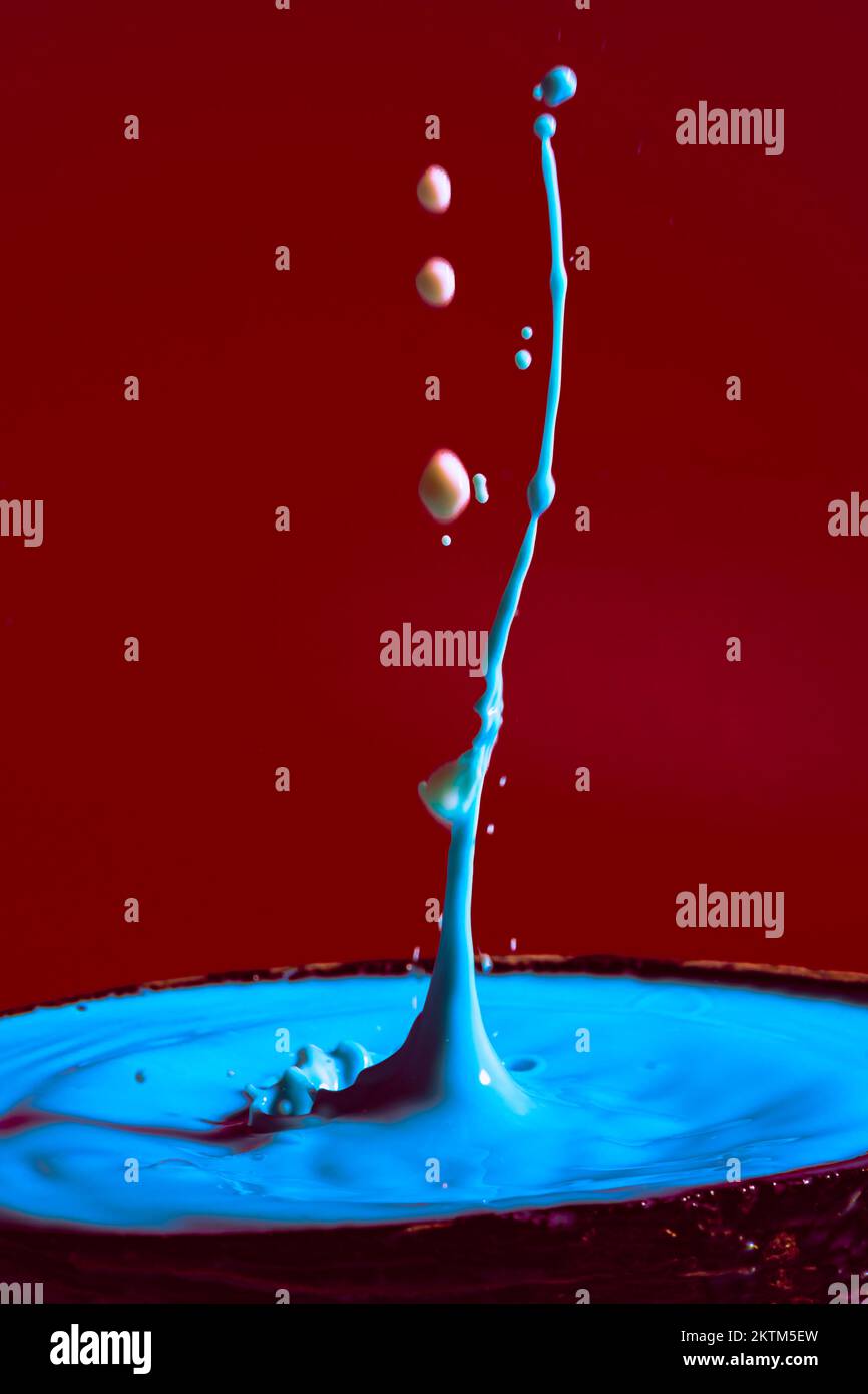 collision of moving water drops of blue color on a purple red ...