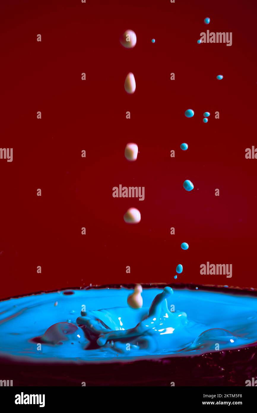 collision of moving water drops of blue color on a purple red ...