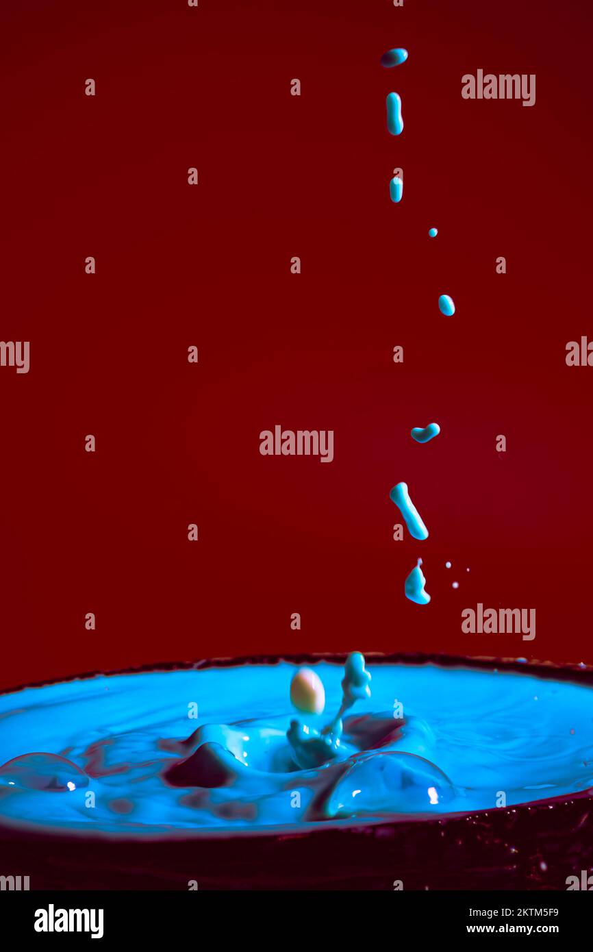 collision of moving water drops of blue color on a purple red ...