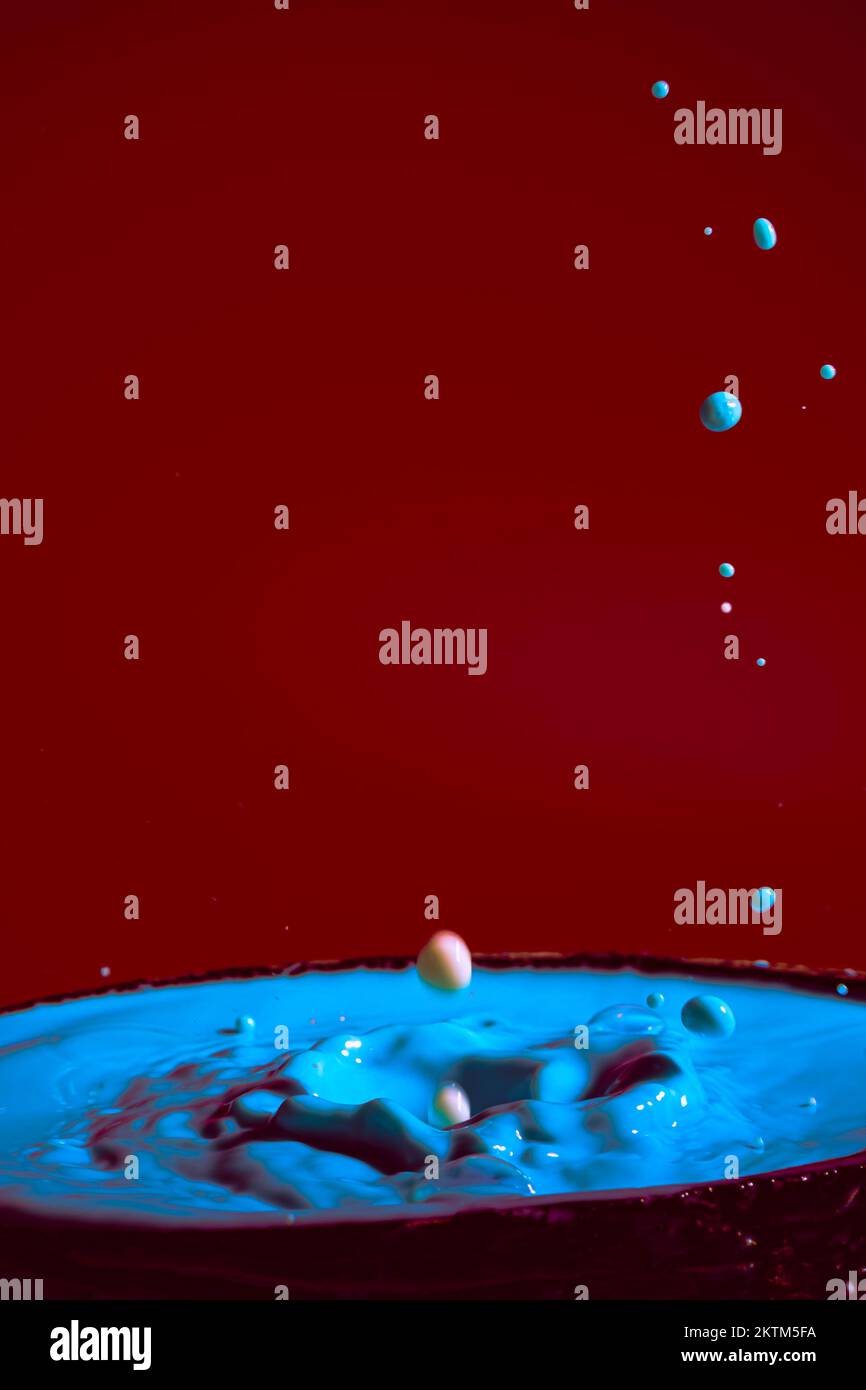 collision of moving water drops of blue color on a purple red ...