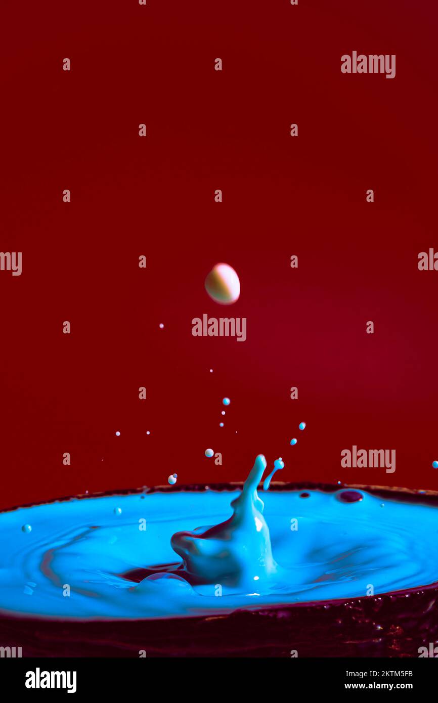 collision of moving water drops of blue color on a purple red ...