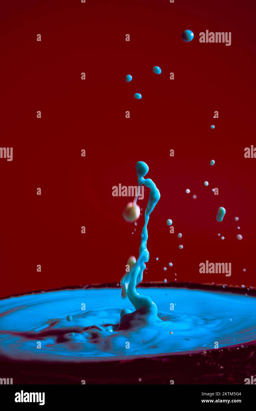 collision of moving water drops of blue color on a purple red ...