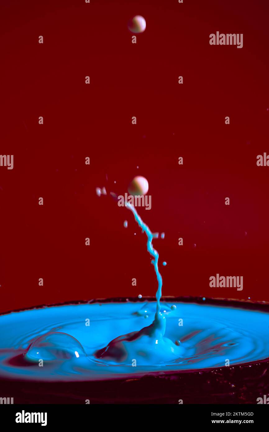 collision of moving water drops of blue color on a purple red ...