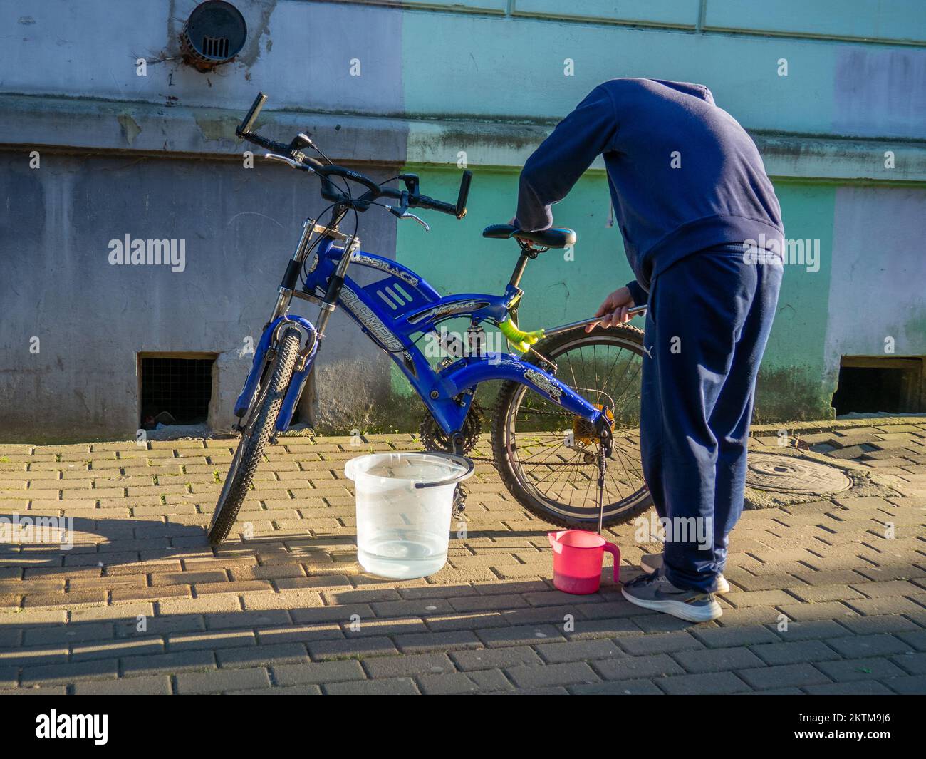 A man cleans his bike on the street. Transport service. Bicycle ...