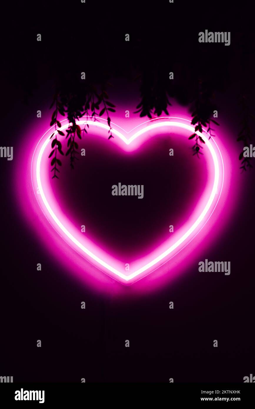 Neon pink heart on black wall with copy space Stock Photo - Alamy