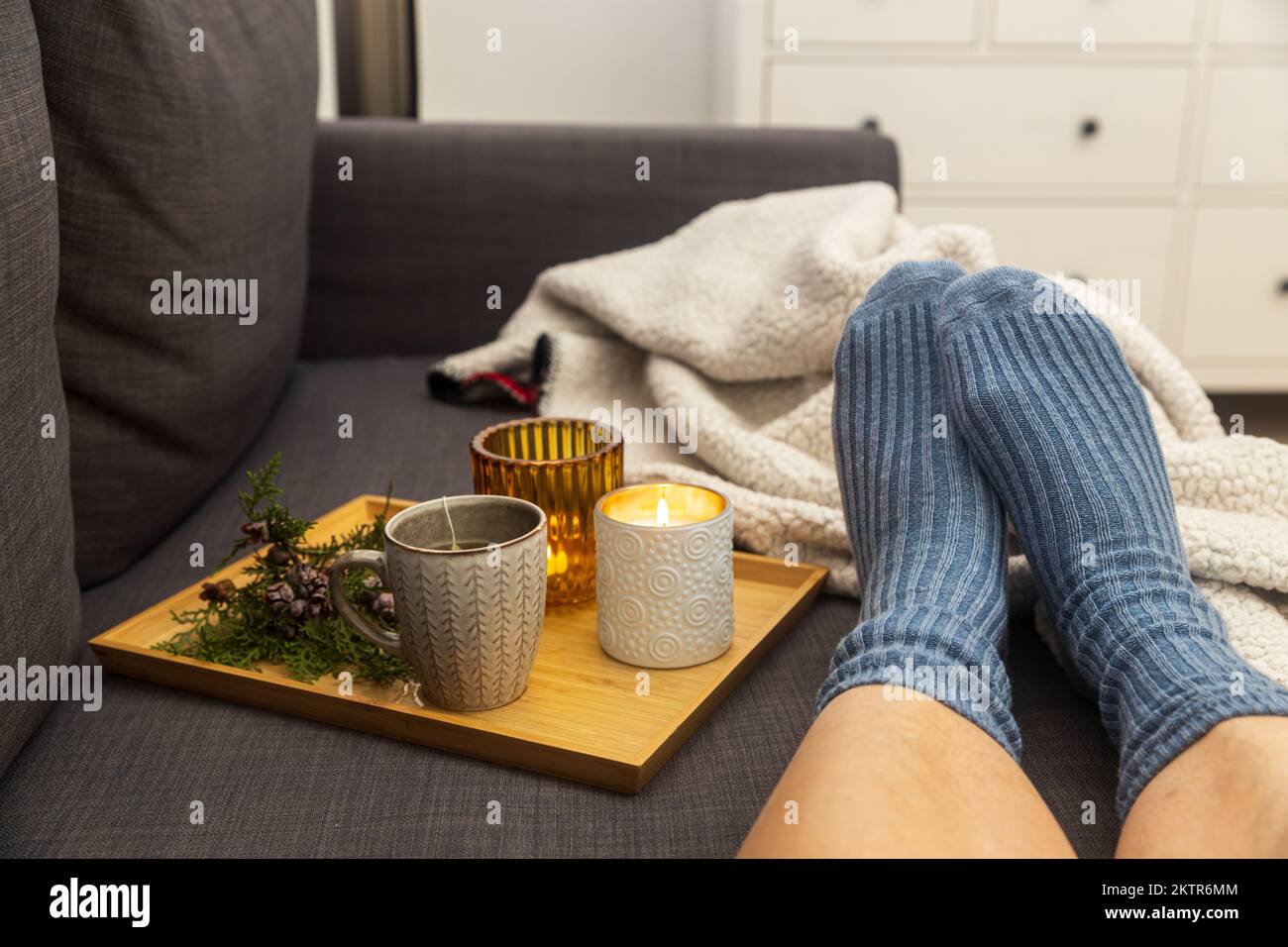 Soft photo of a woman`s legs in woolen blue socks on the sofa with a ...