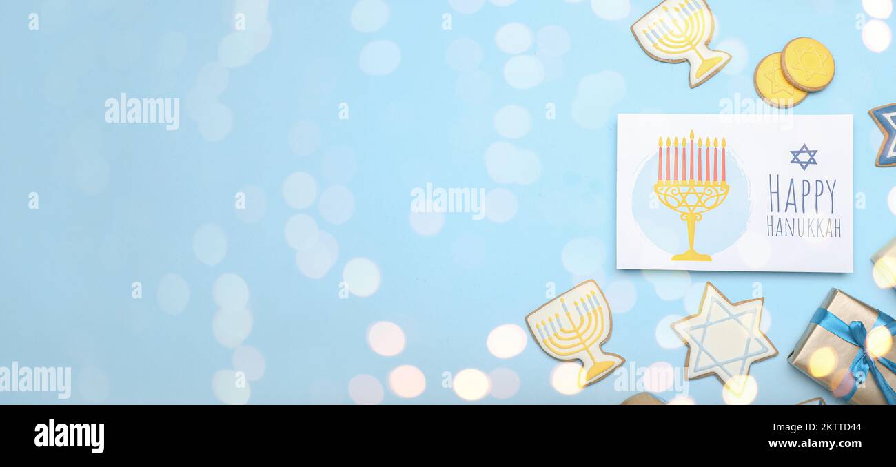 Different symbols of Hanukkah and greeting card on light blue ...