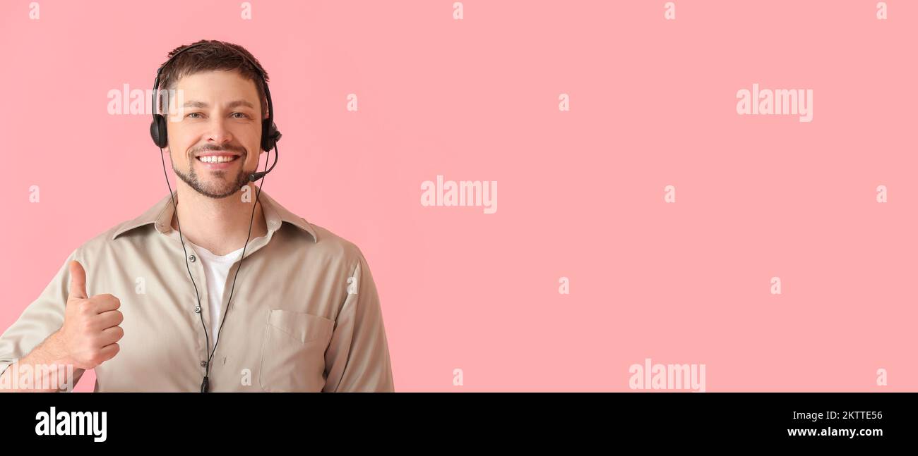 Male technical support agent showing thumb-up on pink background with ...